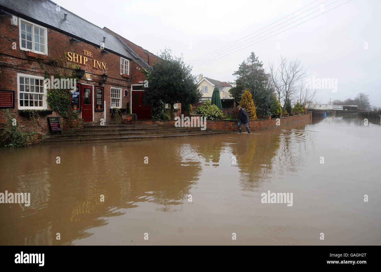 A man makes his way through the flood water to the Ship Inn pub in ...