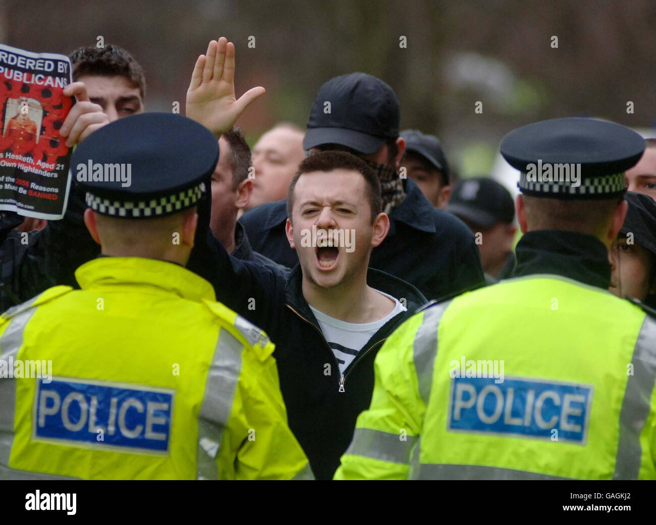 Protesters shout and gesture behind rows of police officers at a parade ...