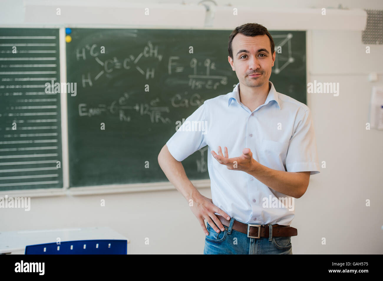 Young teacher near chalkboard in school classroom talking to class ...