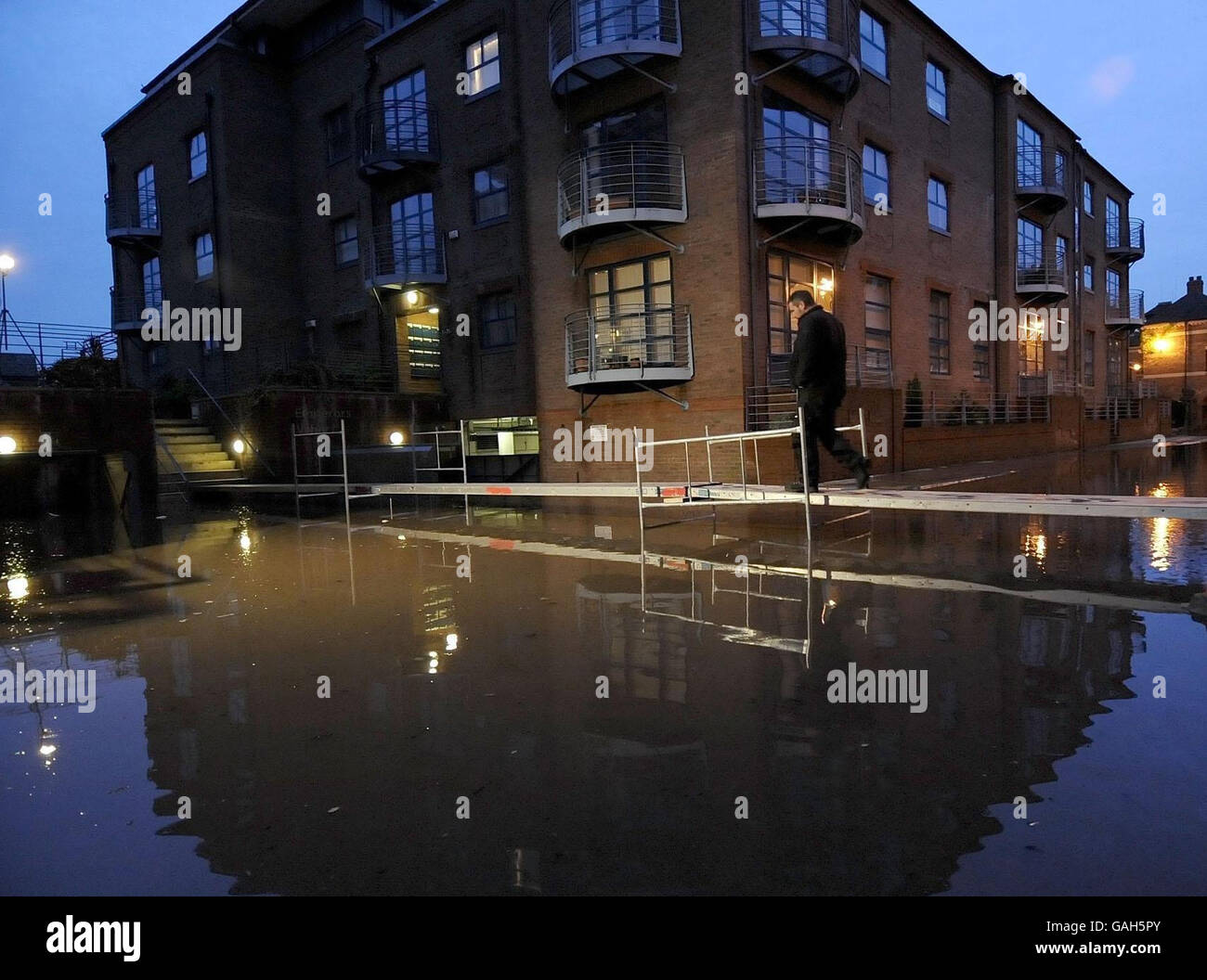 A man uses a raised walkway erected above a flooded street in York ...