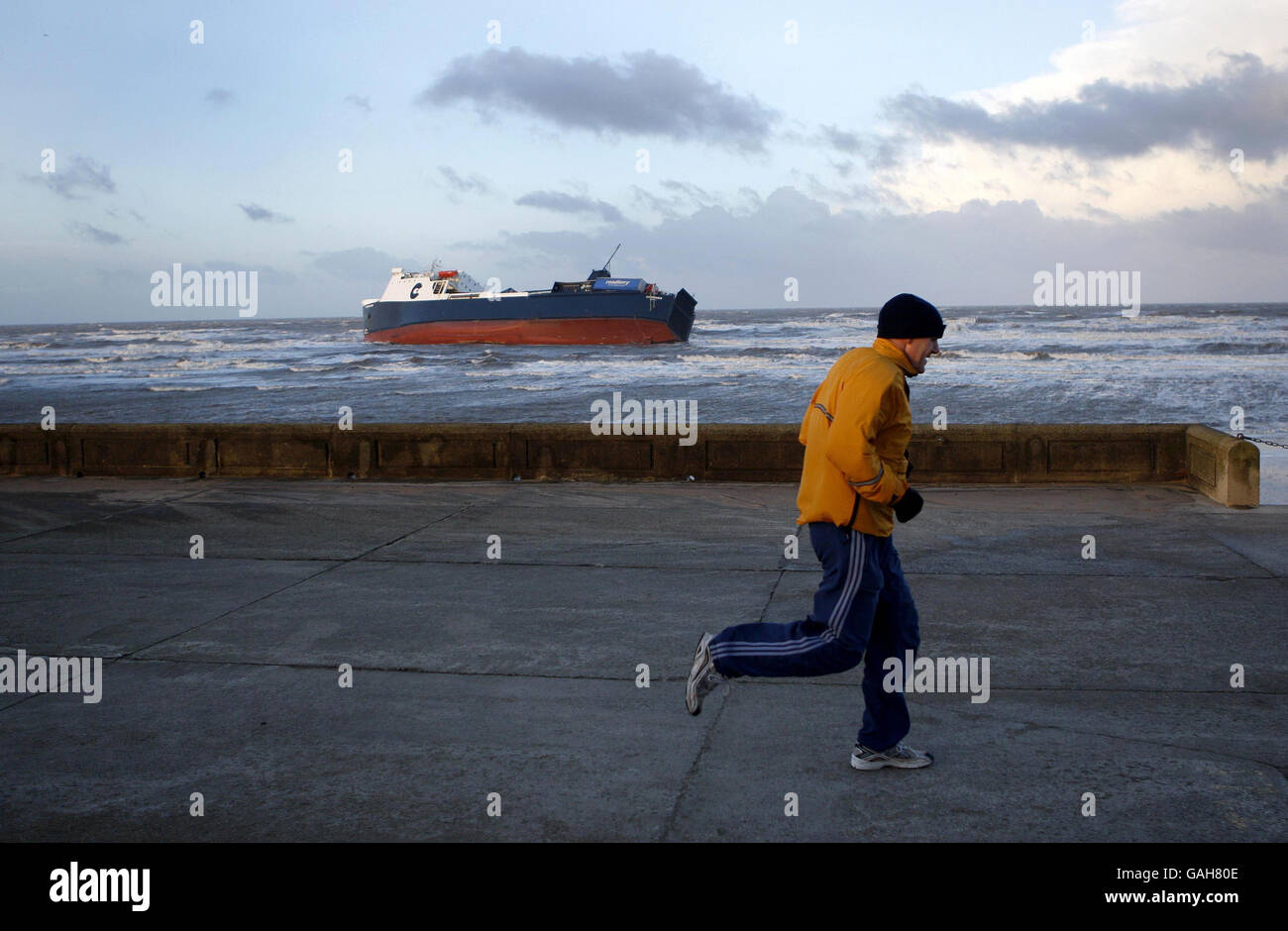 A jogger runs past the cargo ship Riverdance which has run aground at ...