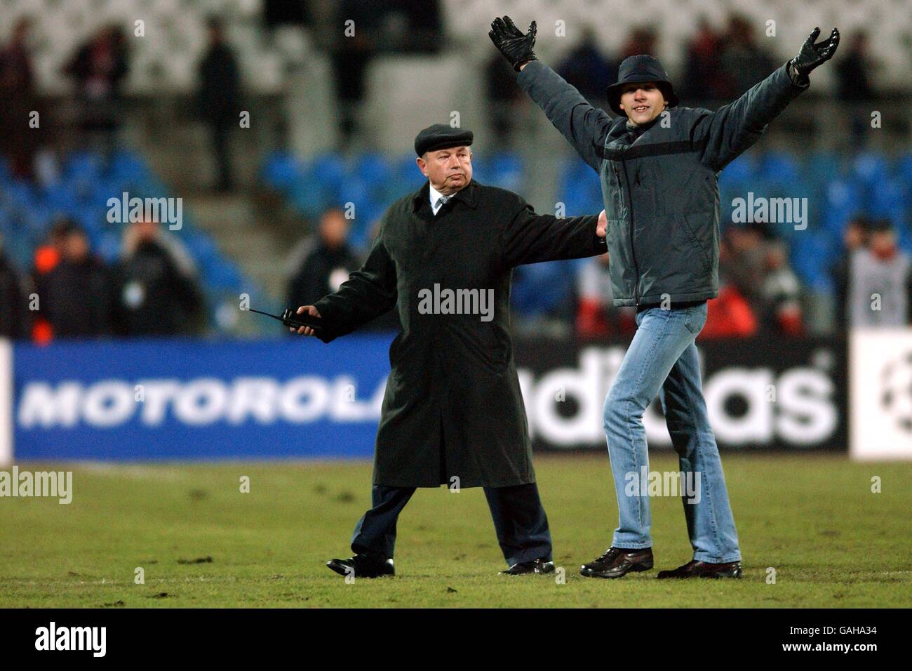 A Liverpool fan is led off the pitch by a Moscow security guard Stock ...