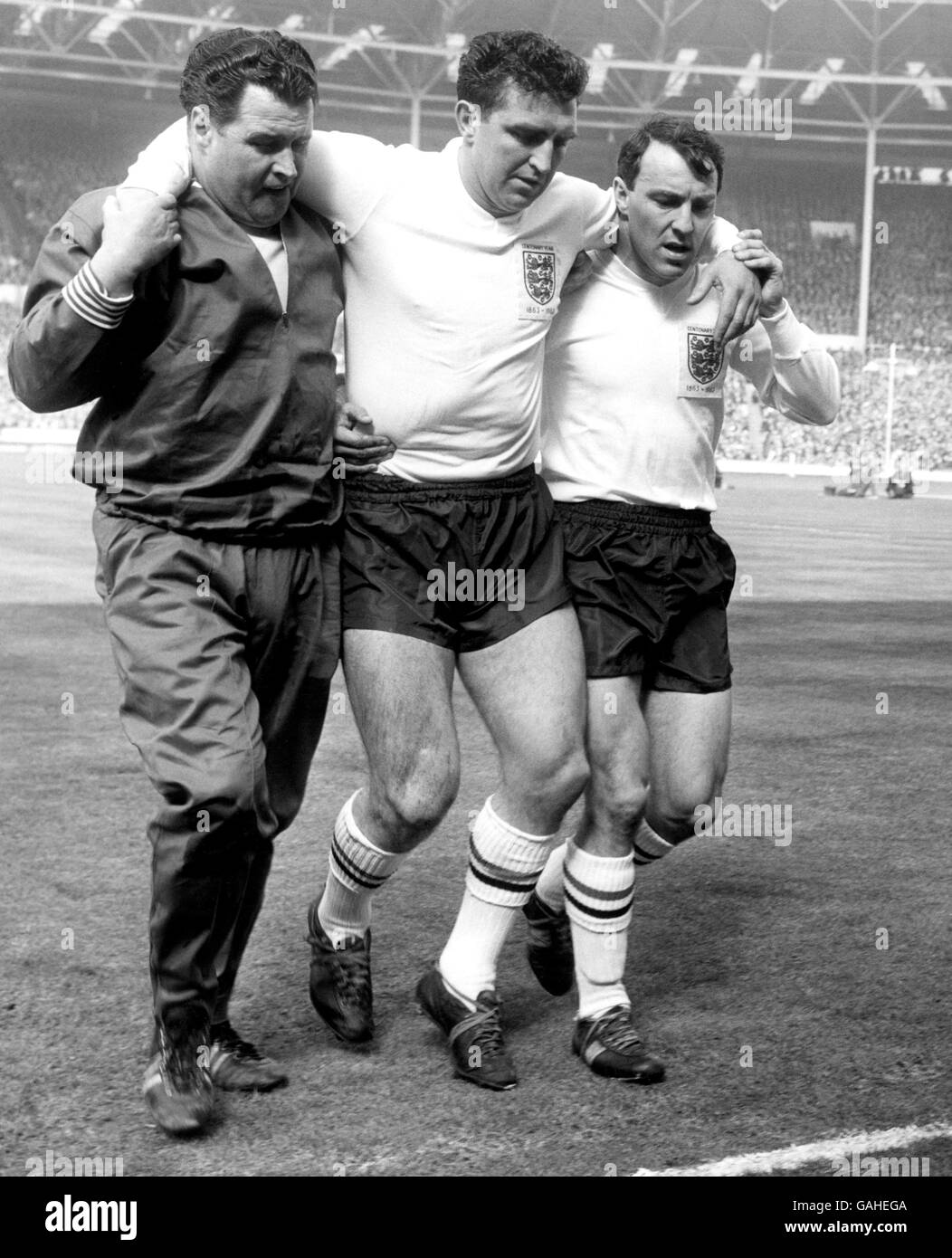 England's Bobby Smith (c) is helped off the pitch by teammate Jimmy ...