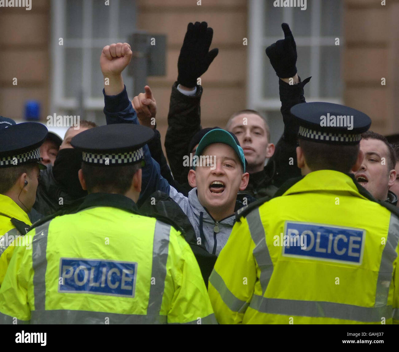 Protesters shout and gesture behind rows of police officers at a parade ...