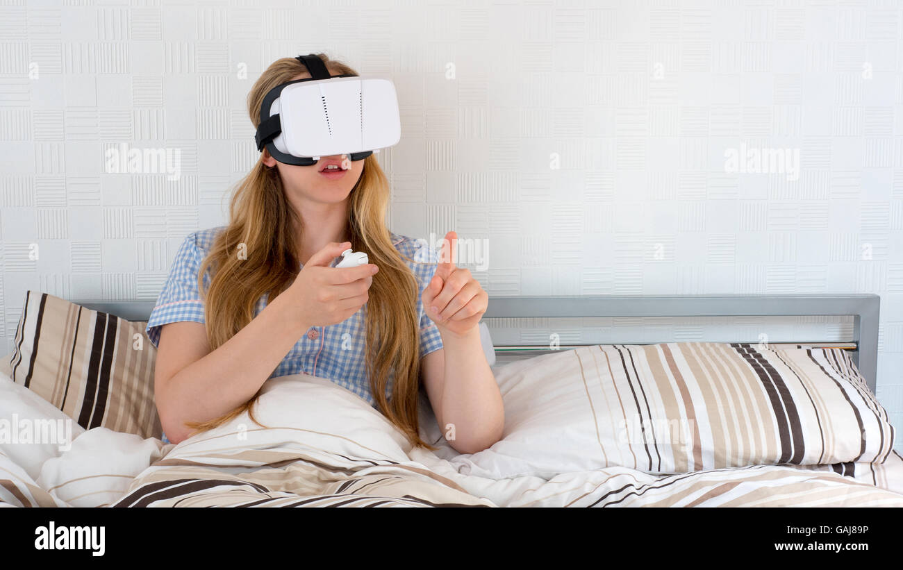 Beautiful woman using VR headset in bed Stock Photo - Alamy