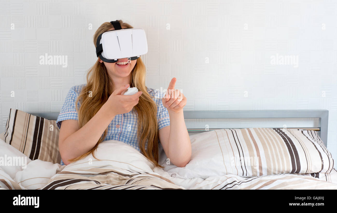 Beautiful woman using VR headset in bed Stock Photo - Alamy