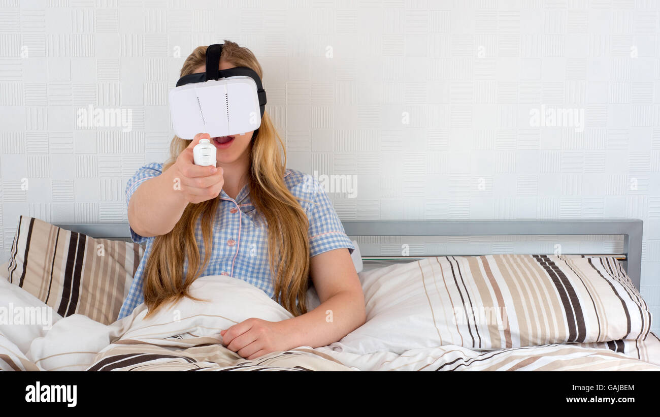 Beautiful woman using VR headset in bed Stock Photo - Alamy