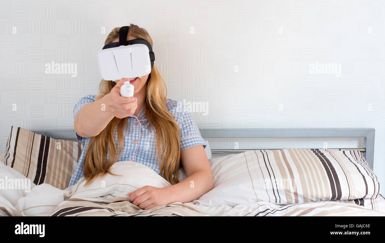 Beautiful woman using VR headset in bed Stock Photo - Alamy