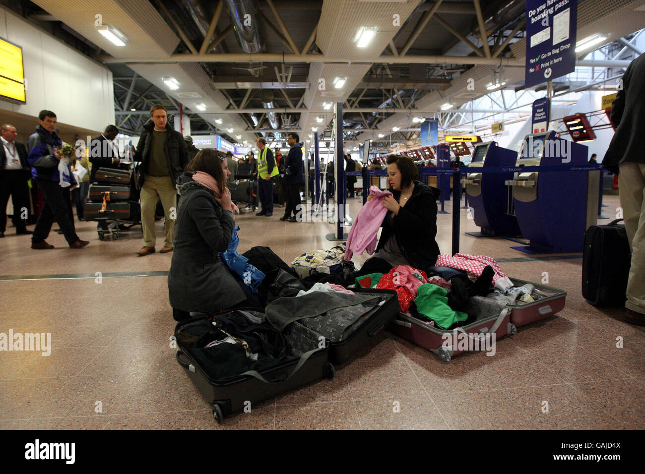 Passengers sort through their luggage after being delayed by a baggage ...