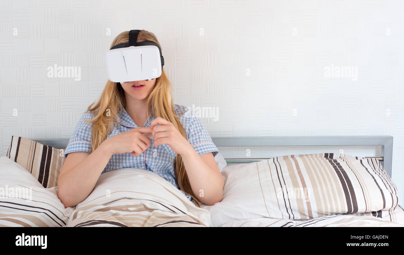 Beautiful woman using VR headset in bed Stock Photo - Alamy