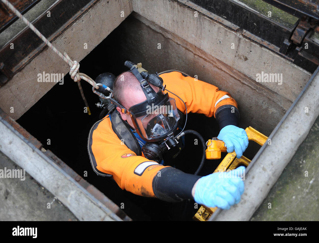 A member of the Police Underwater Search Unit searches a storm drain in ...