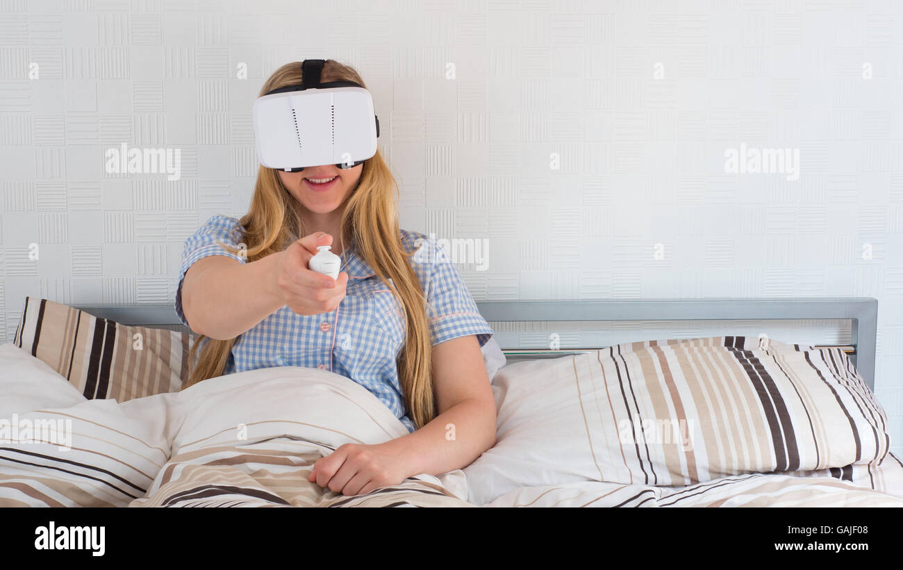 Beautiful woman using VR headset in bed Stock Photo - Alamy