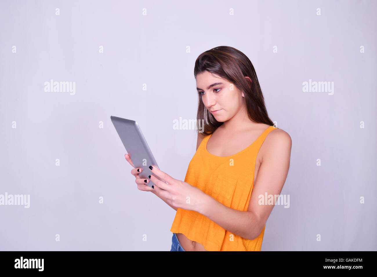 Tablet computer. Young woman holding tablet computer isolated on grey background. Casual ...