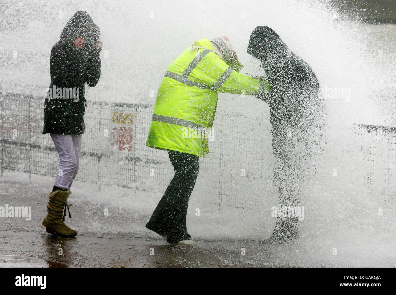 A family battle the elements as waves crash over the seafront in Dover ...
