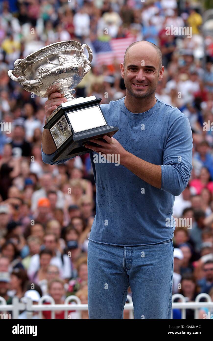 Andre Agassi (USA) holds the winner trophy above the crowd after ...