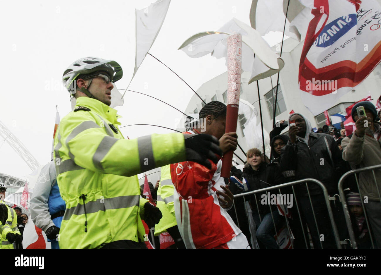 Police protect young torch bearer Cheyenne Green as she runs with the ...