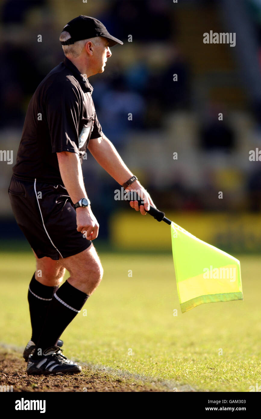 The assistant referee wearing a cap to keep the sun out of his eyes ...