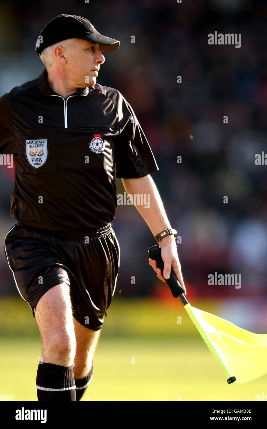 The assistant referee wearing a cap to keep the sun out of his eyes ...