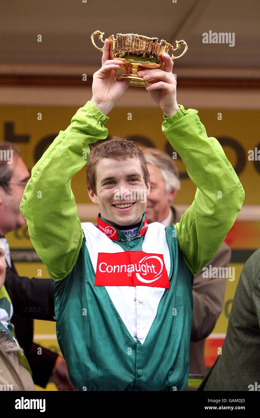 Jockey Sam Thomas celebrates with the trophy after riding to glory on ...
