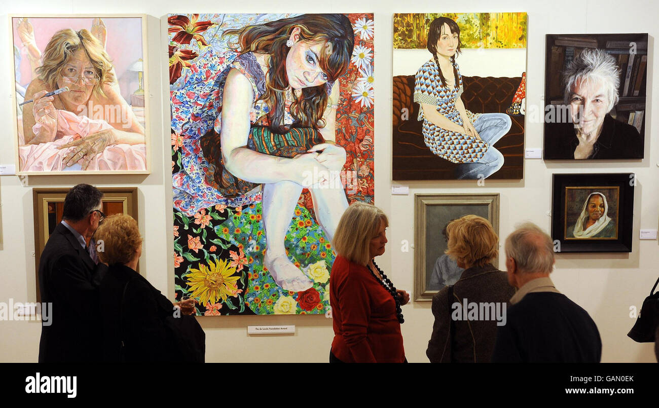 Visitors study the artwork at the Mall Galleries in central London ...