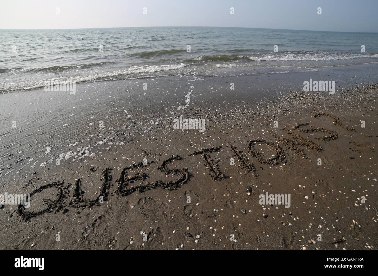 Questions with question mark written in large letters on the sand of ...