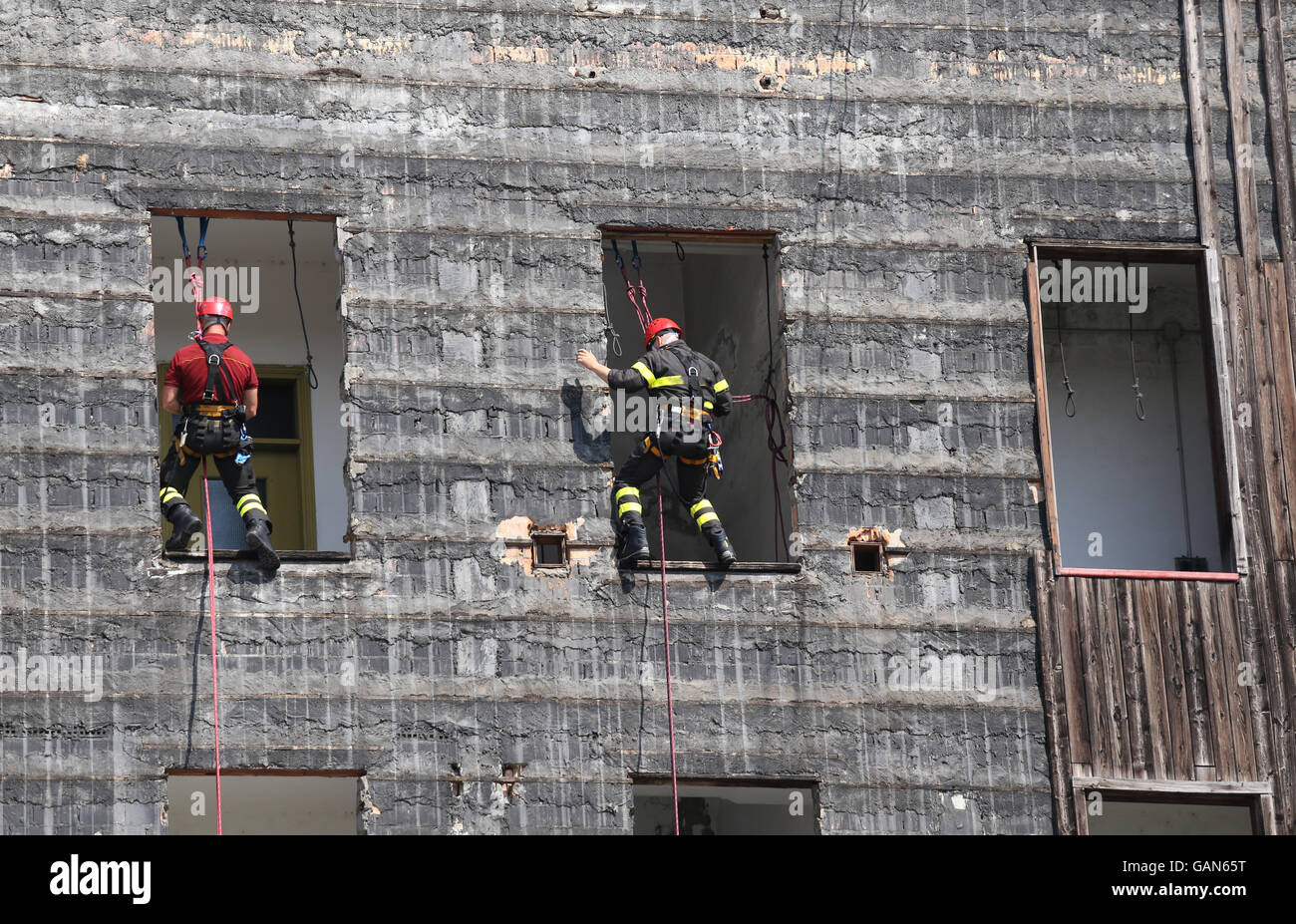 two bold and daring climbers of firefighters climbing a wall of an ...