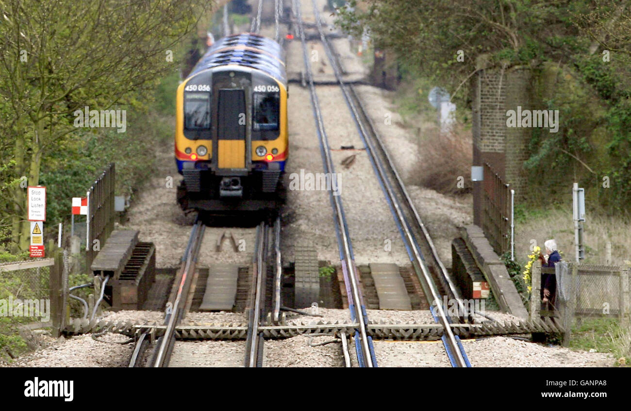 A couple wait for a train to pass at a rail foot crossing near to Moor ...