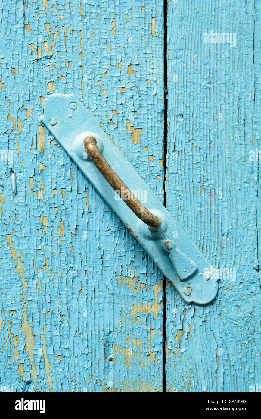 Single old metal door handle on faded aged light blue paint. Copy space ...