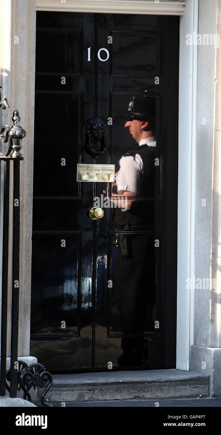 A uniformed Police Officer reflected in the front door of number 10 ...