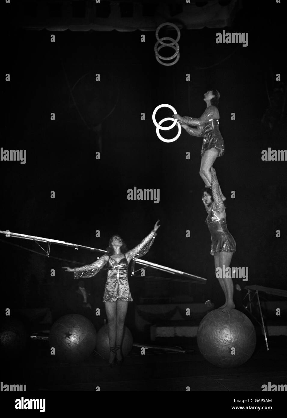 Acrobats balancing on ball juggling hoops standing on shoulders hi-res ...