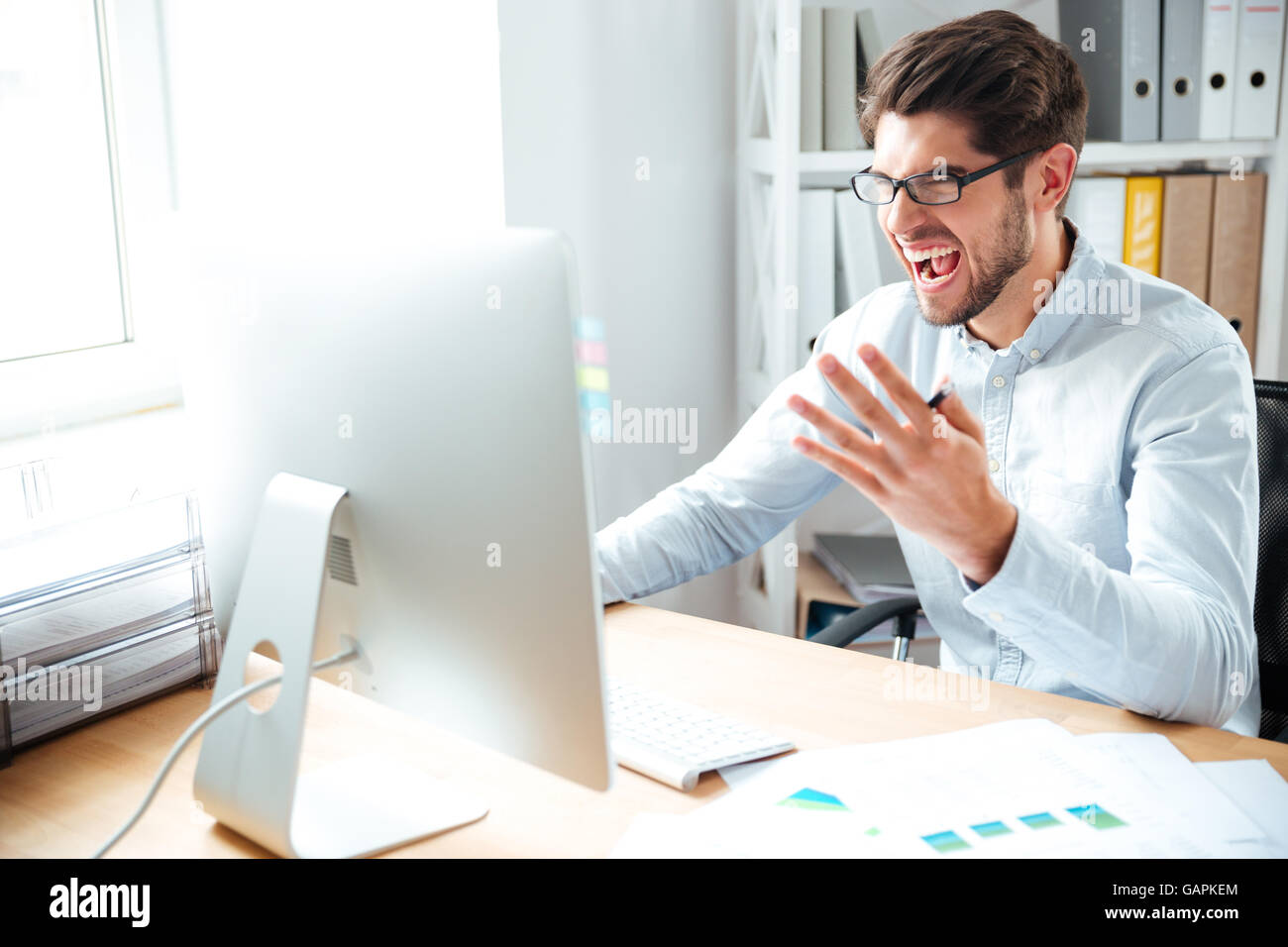 Angry mad young businessman working with computer and shouting in ...