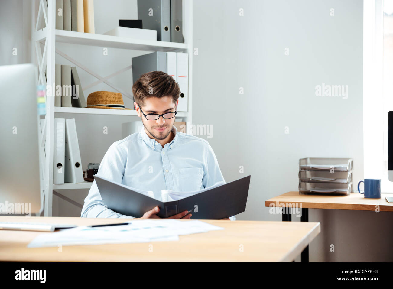 Concentrated young businessman working with documents in folder at ...