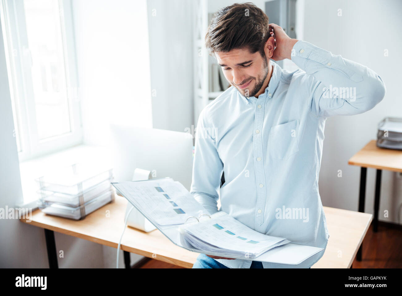 Confused young businessman working with documents in folder Stock Photo ...