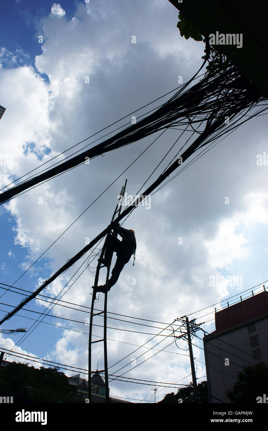 Electrician working among electric wire network in the blue sky as ...