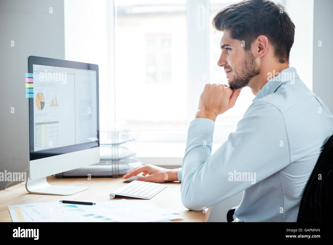 Side view of handsome young smiling businessman in casual cloth sitting ...