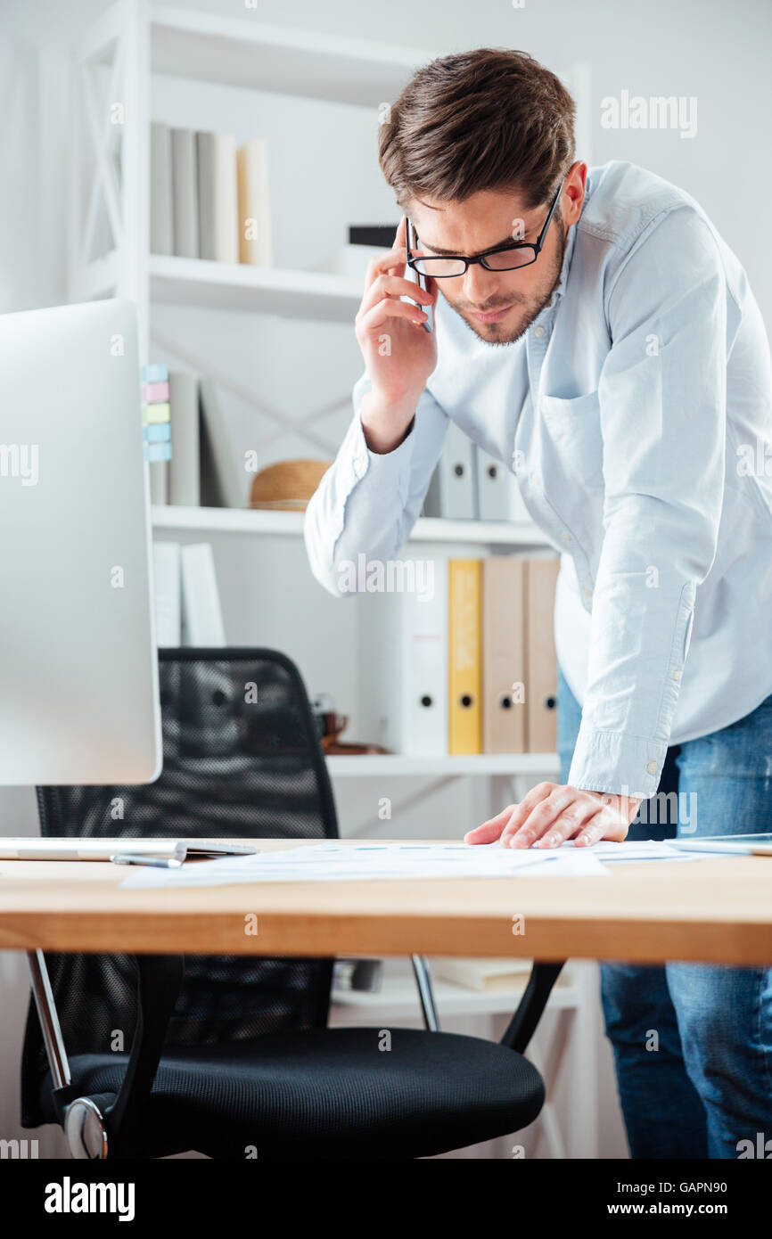 Businessman closing a deal signing documents at desk in office wearing ...