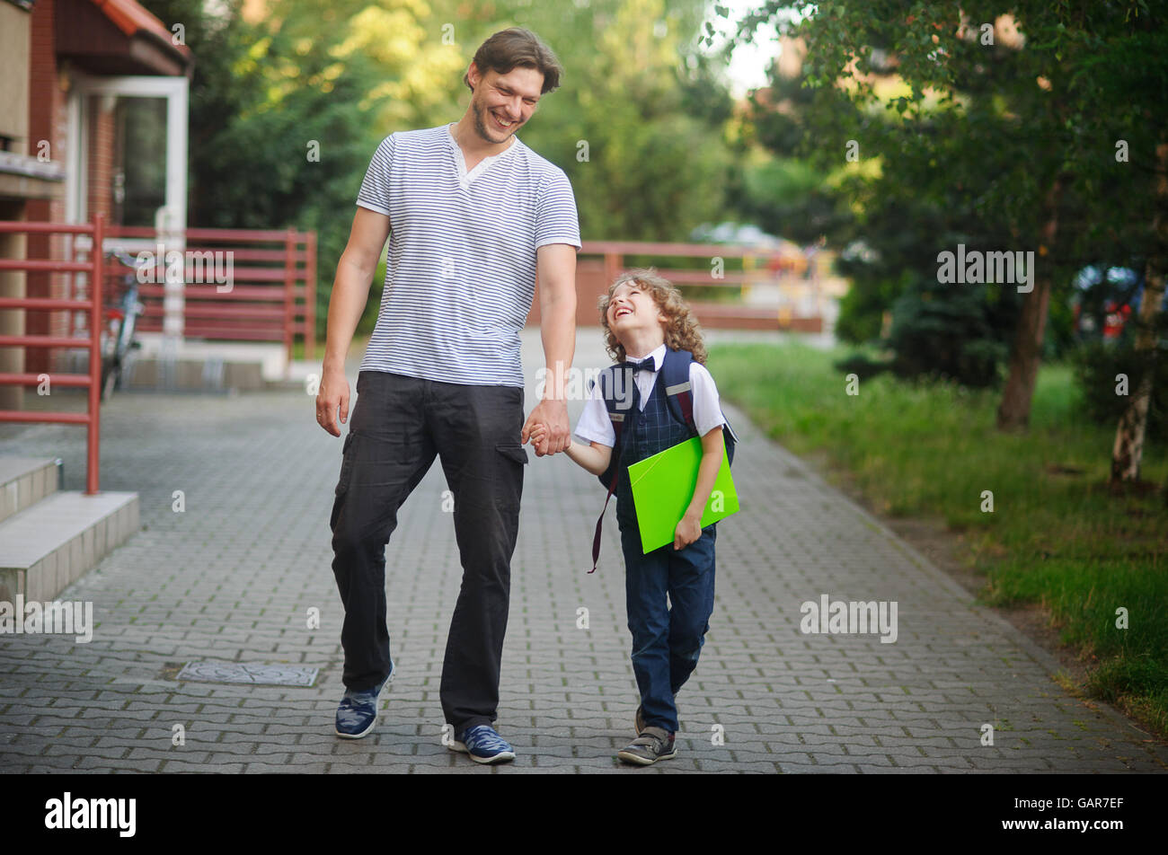Father escorted to school by his son. The tall man tightly holding the ...