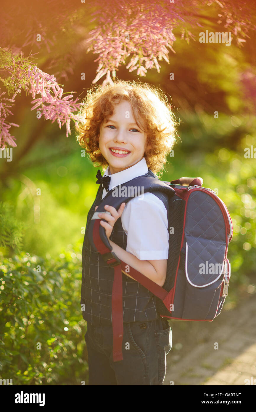 The first grader standing about beautifully blossoming bush. Sunny day ...