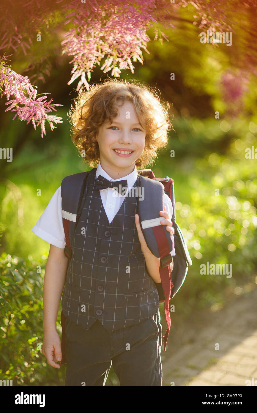 The first grader standing about beautifully blossoming bush. Sunny day ...