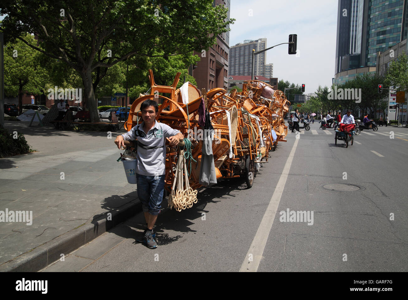 Chinese man stands in front of a long cart that he pulls from one place ...