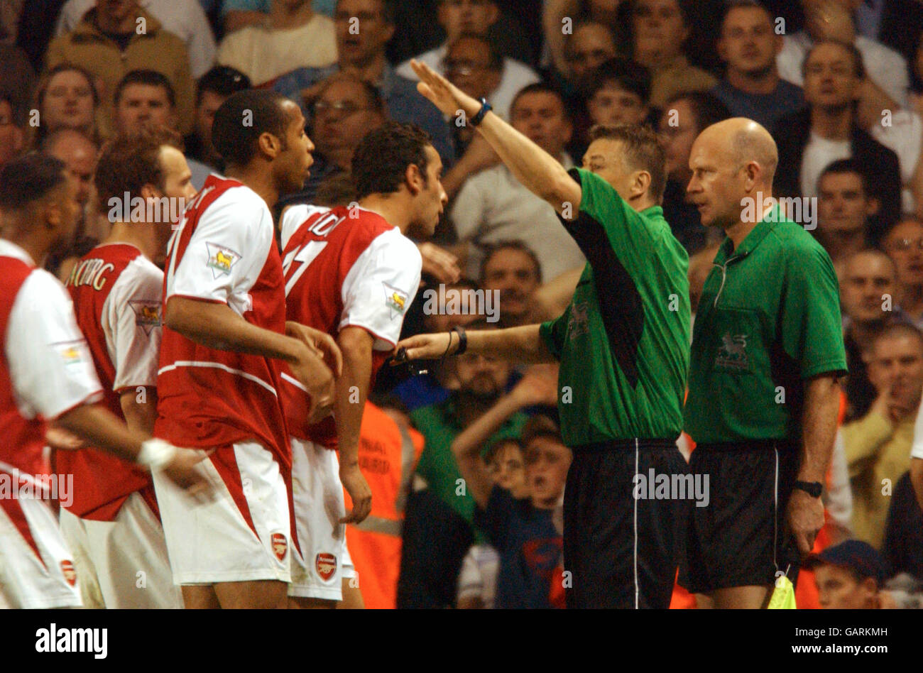 Arsenal players surround Referee Mark Halsey and Assistant Referee ...