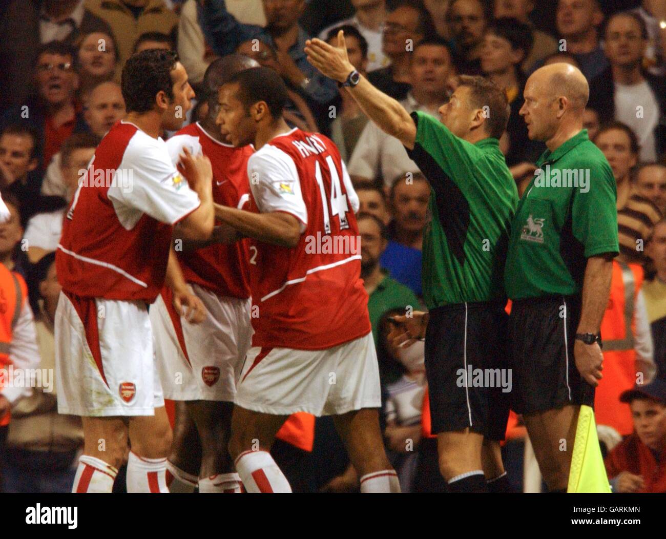 Arsenal players surround Referee Mark Halsey and Assistant Referee ...