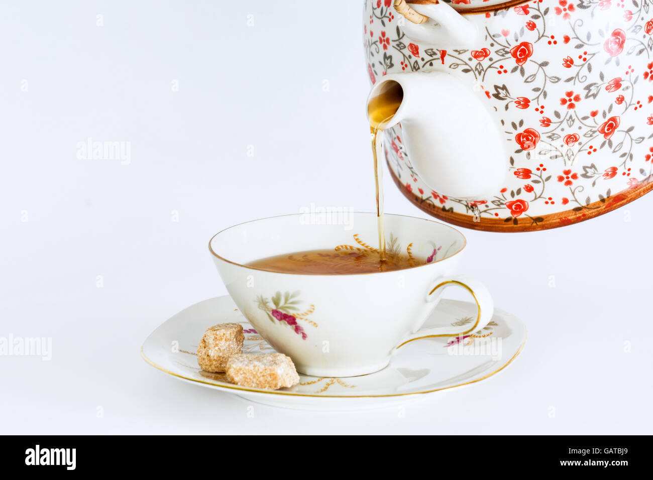 Teapot pouring tea into a cup of tea isolated on white background Stock ...