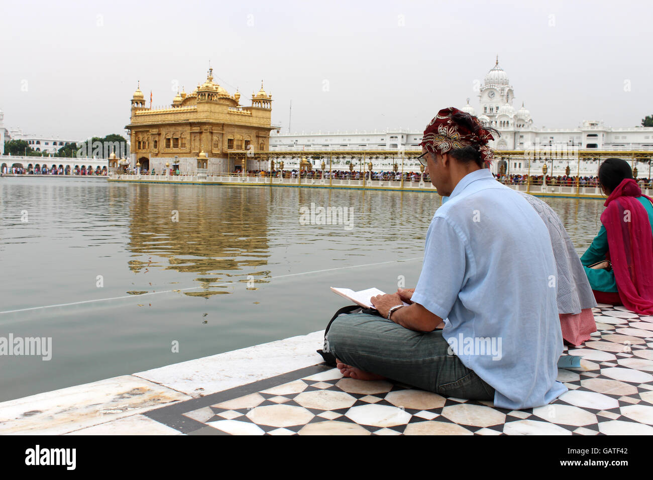 A man is praying in front of the golden temple at Amritsar, Panjab ...