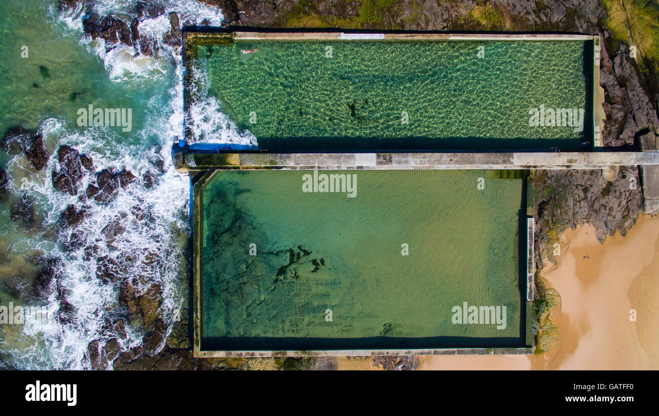 A lone swimmer swims laps in the Austinmer ocean rock pools, viewed ...