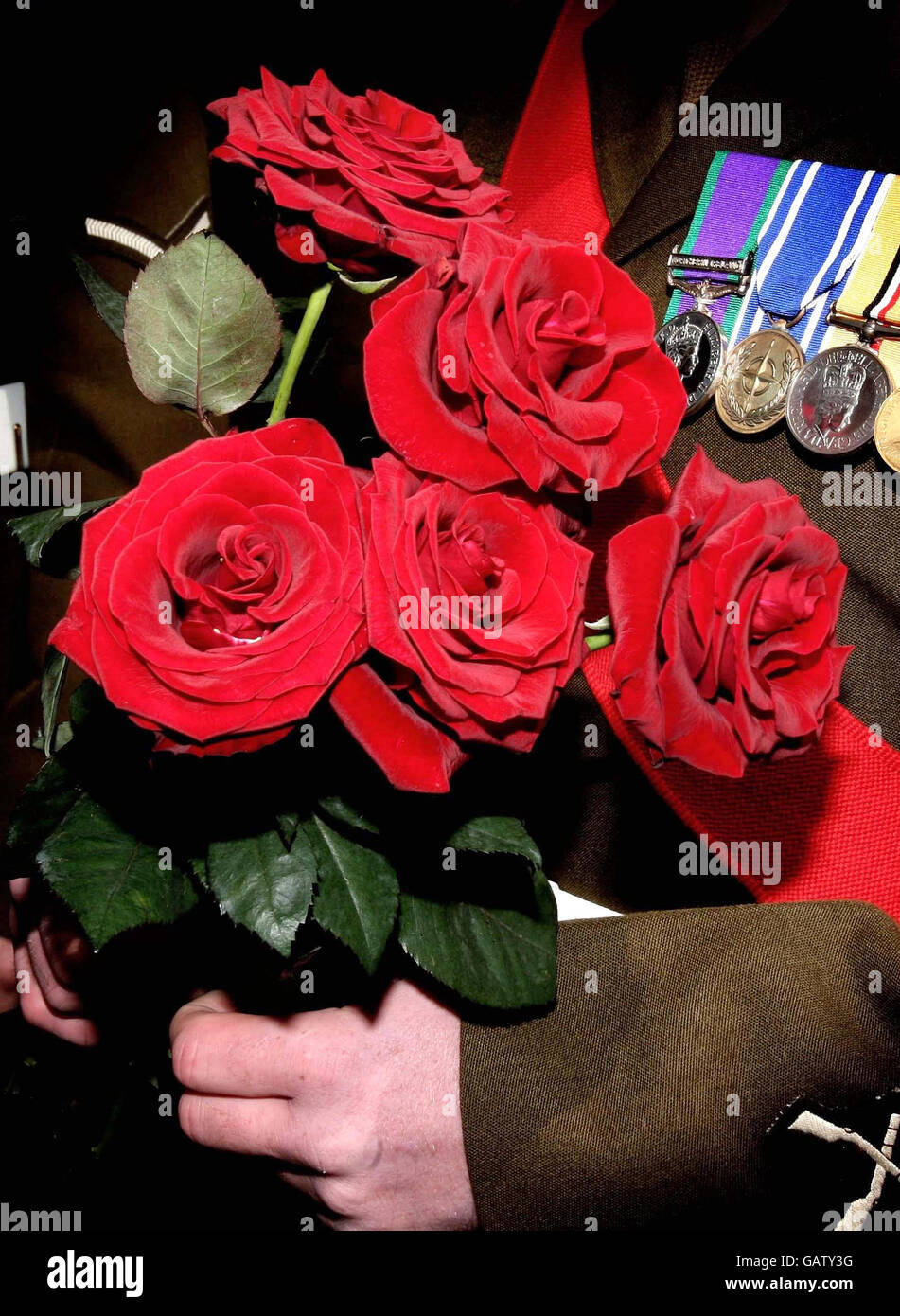 A Serviceman from the Parachute Regiment holds five red roses ...