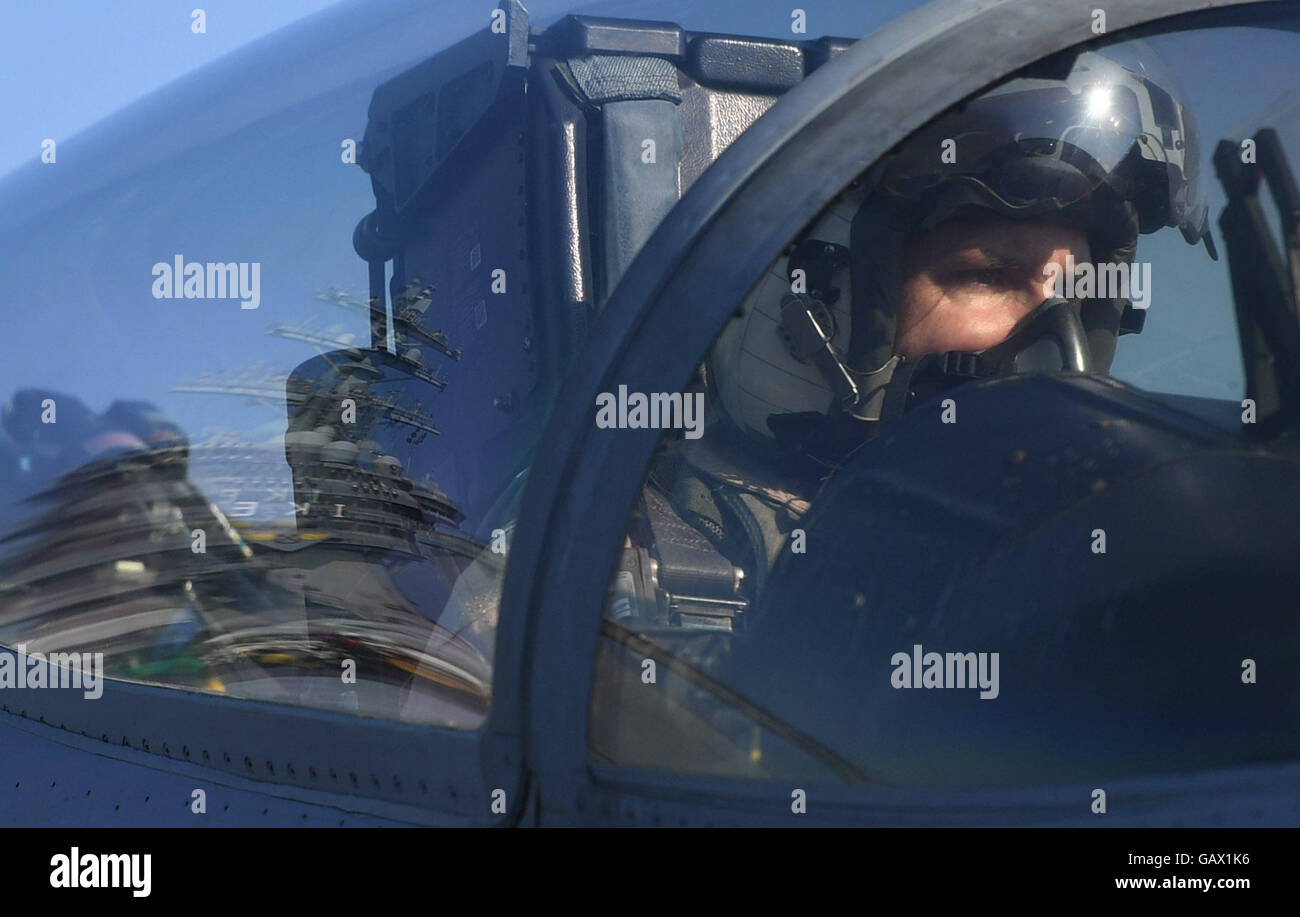 A pilot sits inside a warplane on the deck of aircraft carrier USS ...