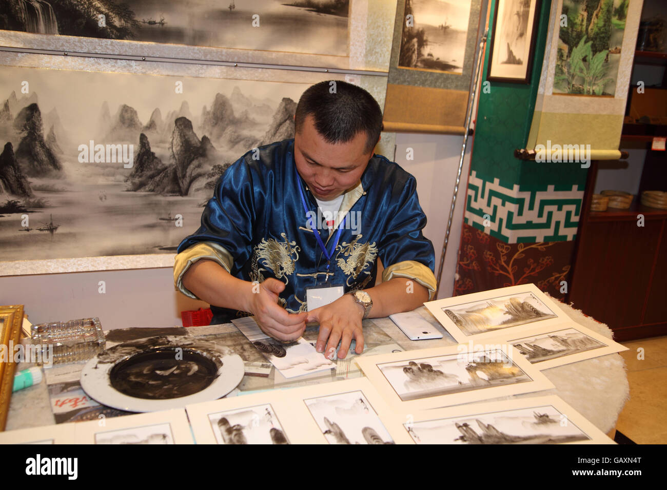 A Chinese artist sits in a gallery, using ink on his pinky he makes ...