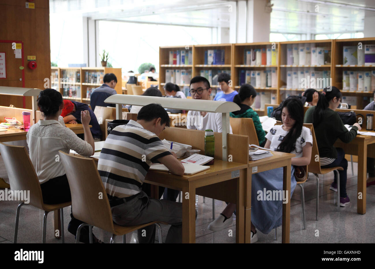 Young Chinese people sit and read in the library. Shenzhen Library ...