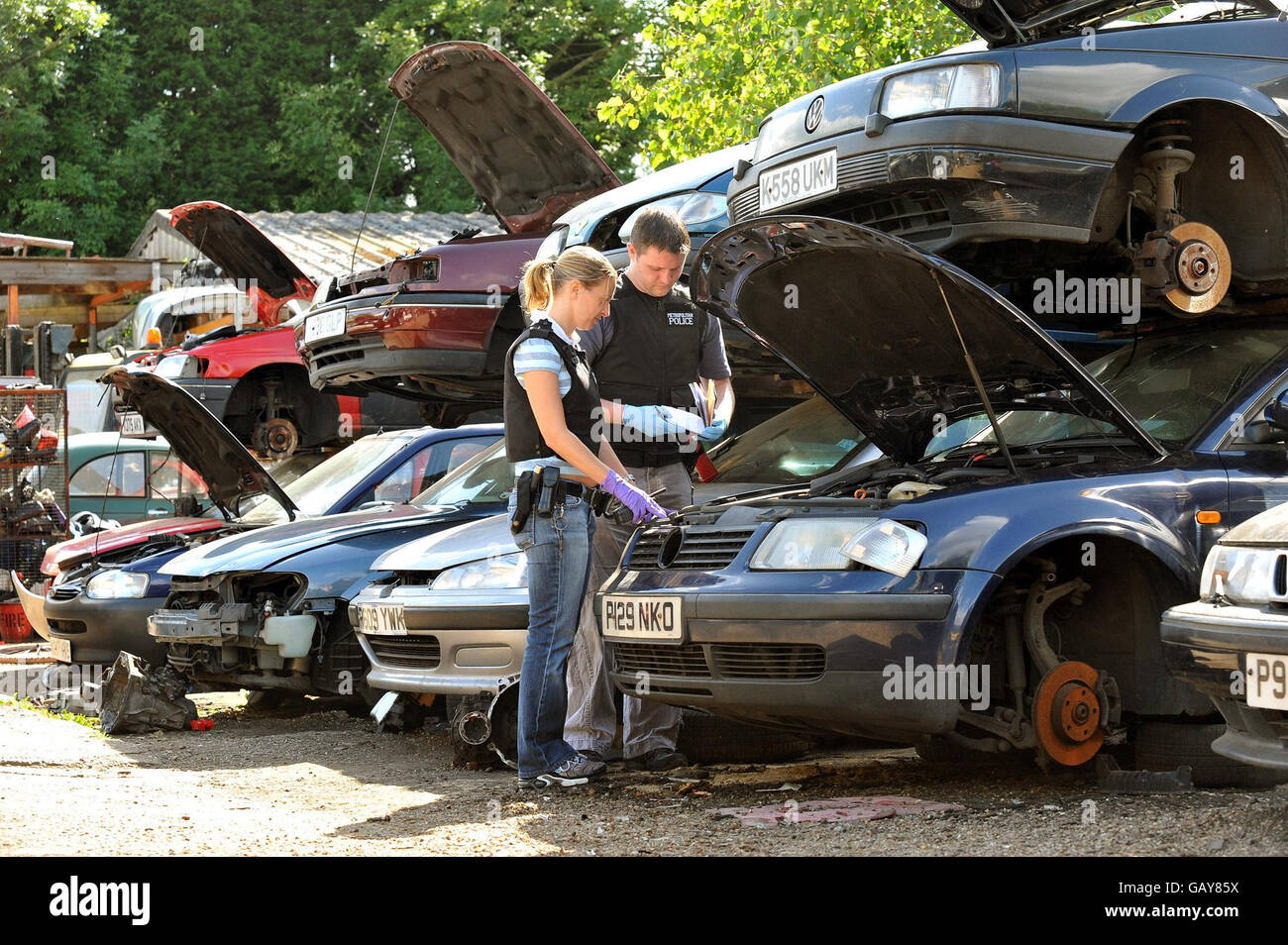 A group of metropolitan police officers check cars in a breakers yard ...